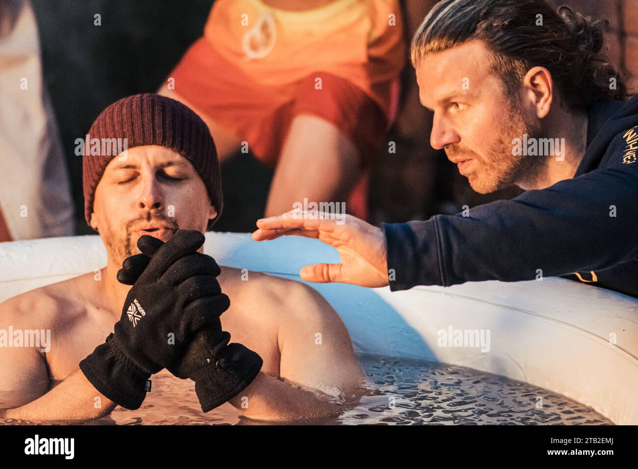 Man wearing hat and gloves ice bathing in the cold water among ice ...