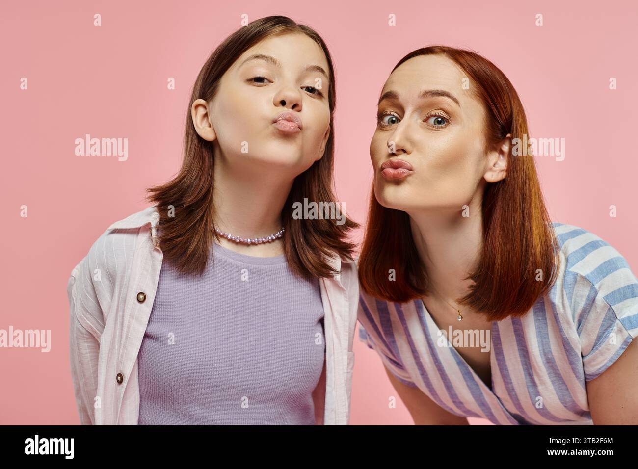 cheerful mother and teenage daughter pouting lips and looking at camera ...