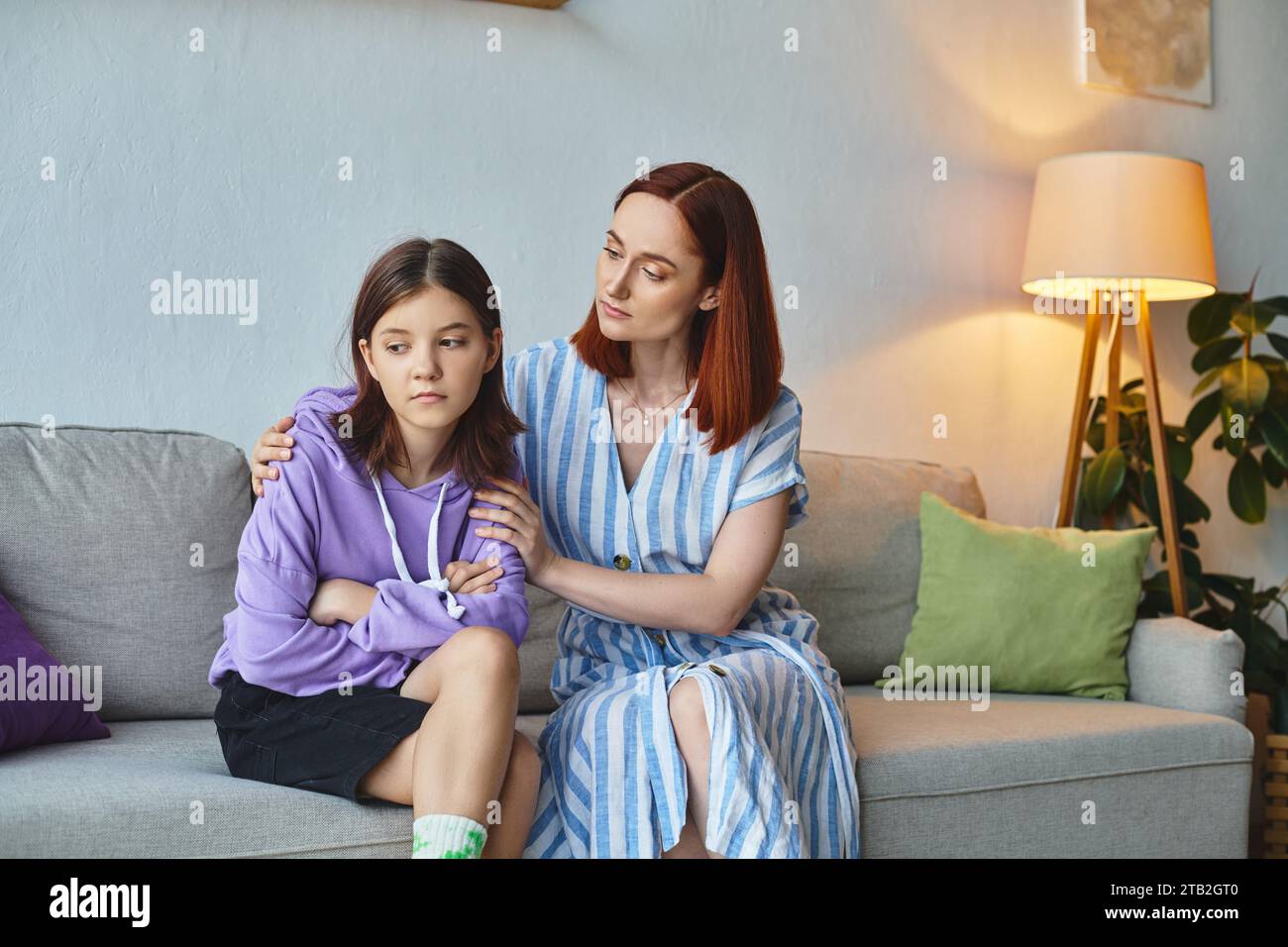 caring mother calming upset teenage daughter sitting on couch in living room, care and support ...