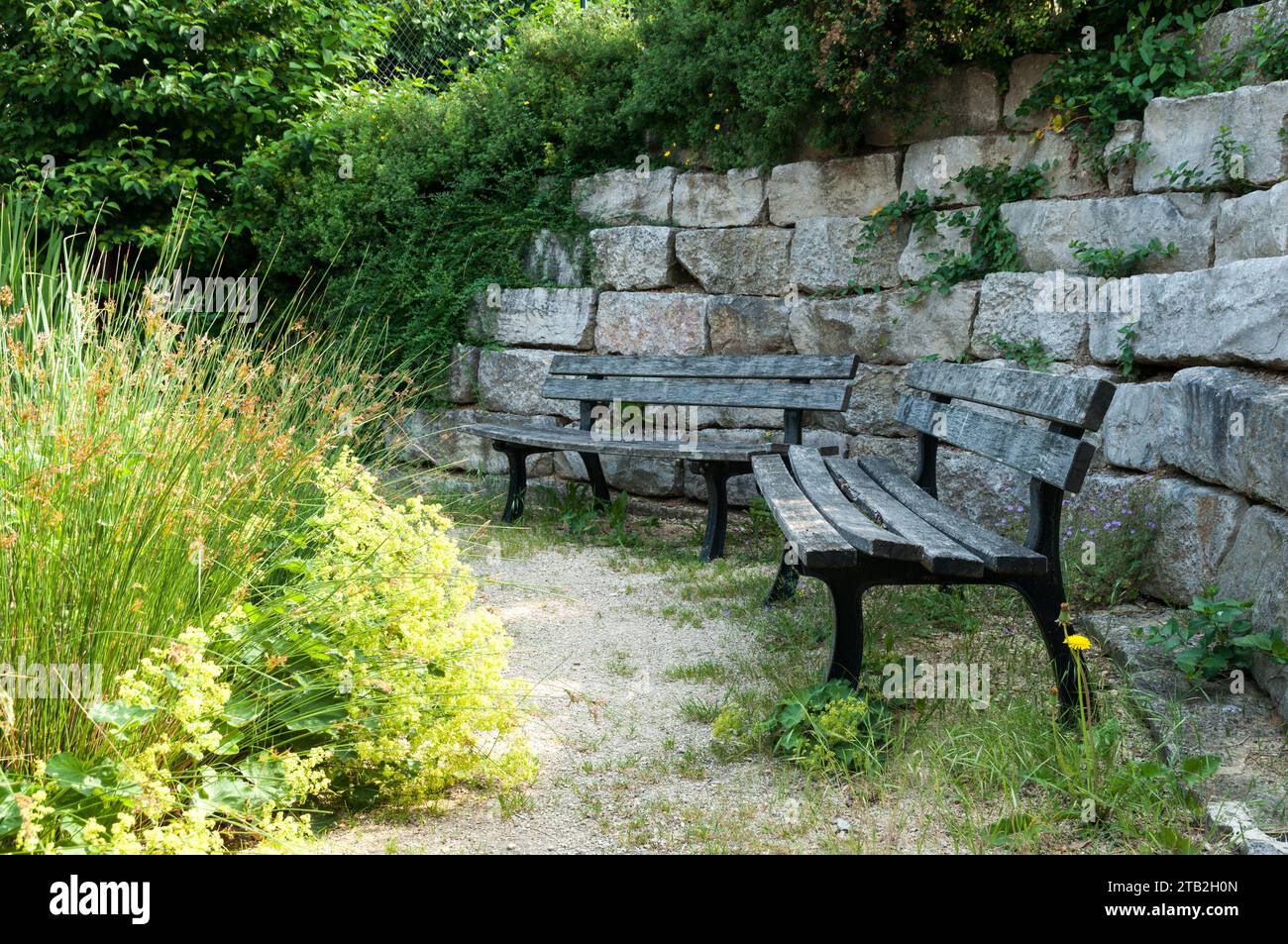 The wooden benches are situated in front of an old stone wall. Germany ...