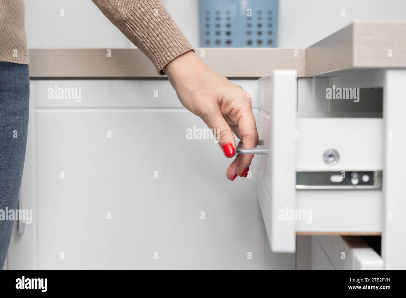 female hand opens kitchen cabinet with utensils. drawer with kitchen ...