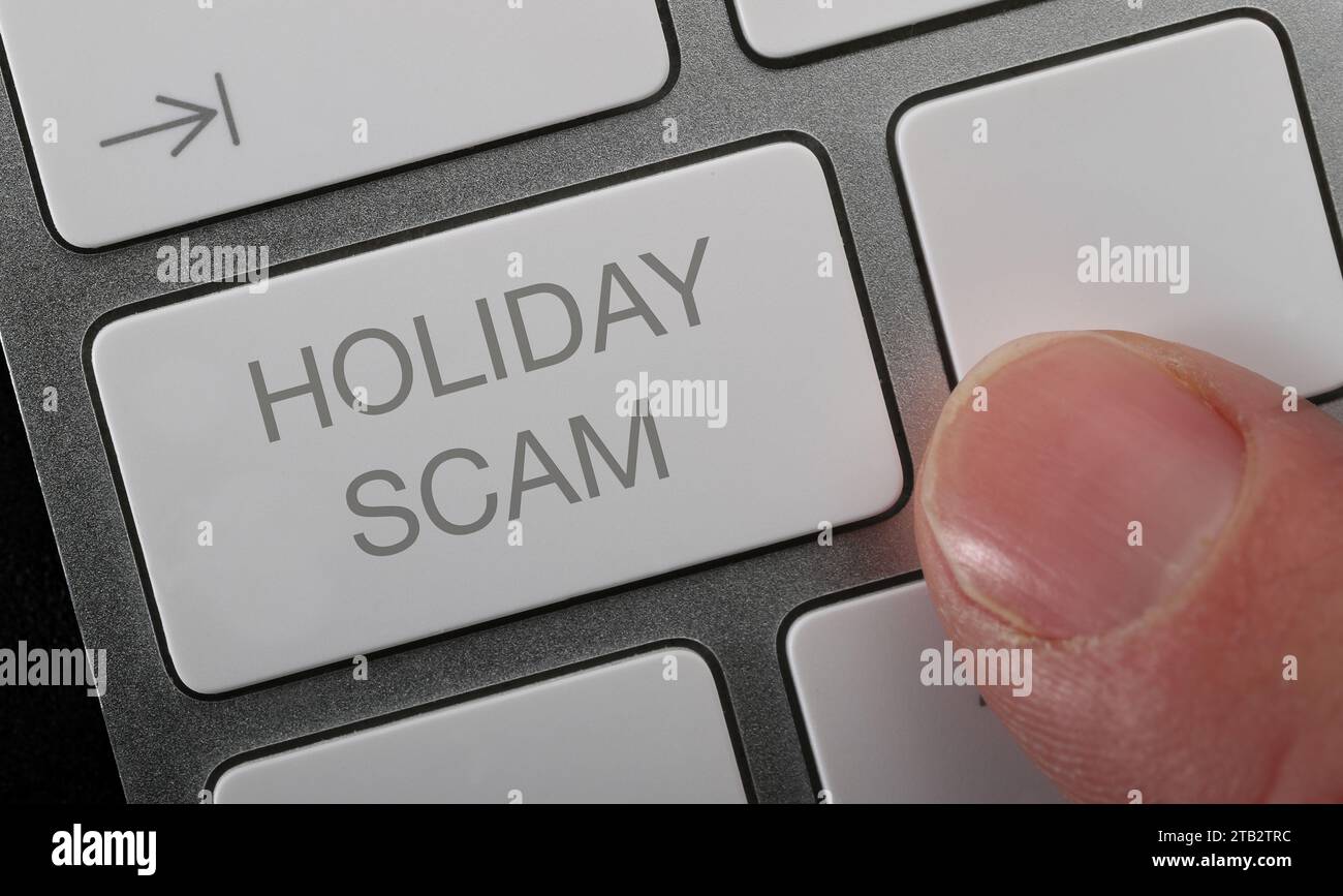 A man pressing a holiday scam button on a compter keyboard to report a ...