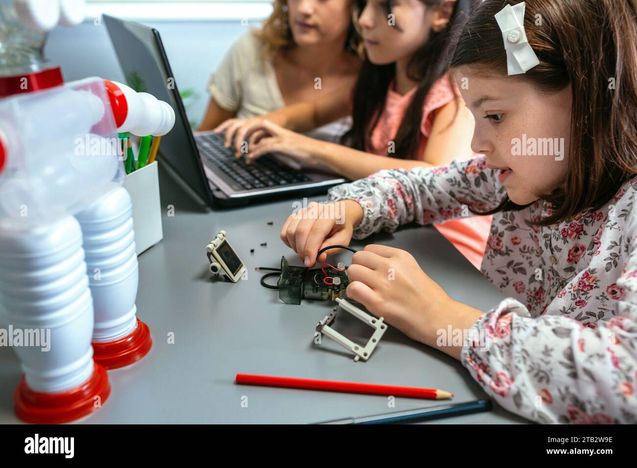 Female student connecting wire on electrical circuit in robotics class ...