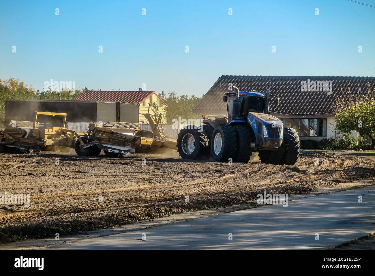 A tractor pulls laser guided scrapers to level a former walnut orchard ...