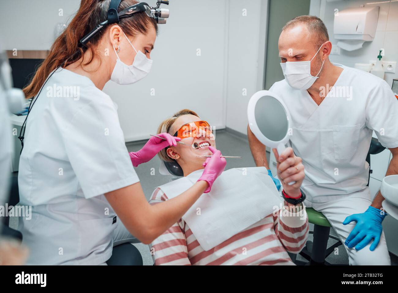 Smiling female lying in stomatology chair, gazing at mirror, female ...