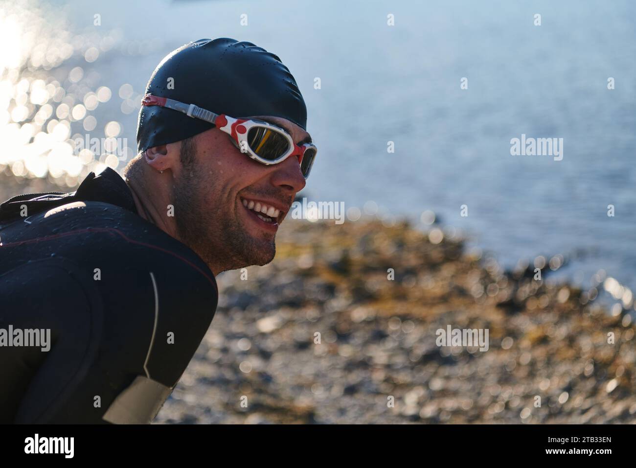 Authentic triathlon athlete getting ready for swimming training on lake ...