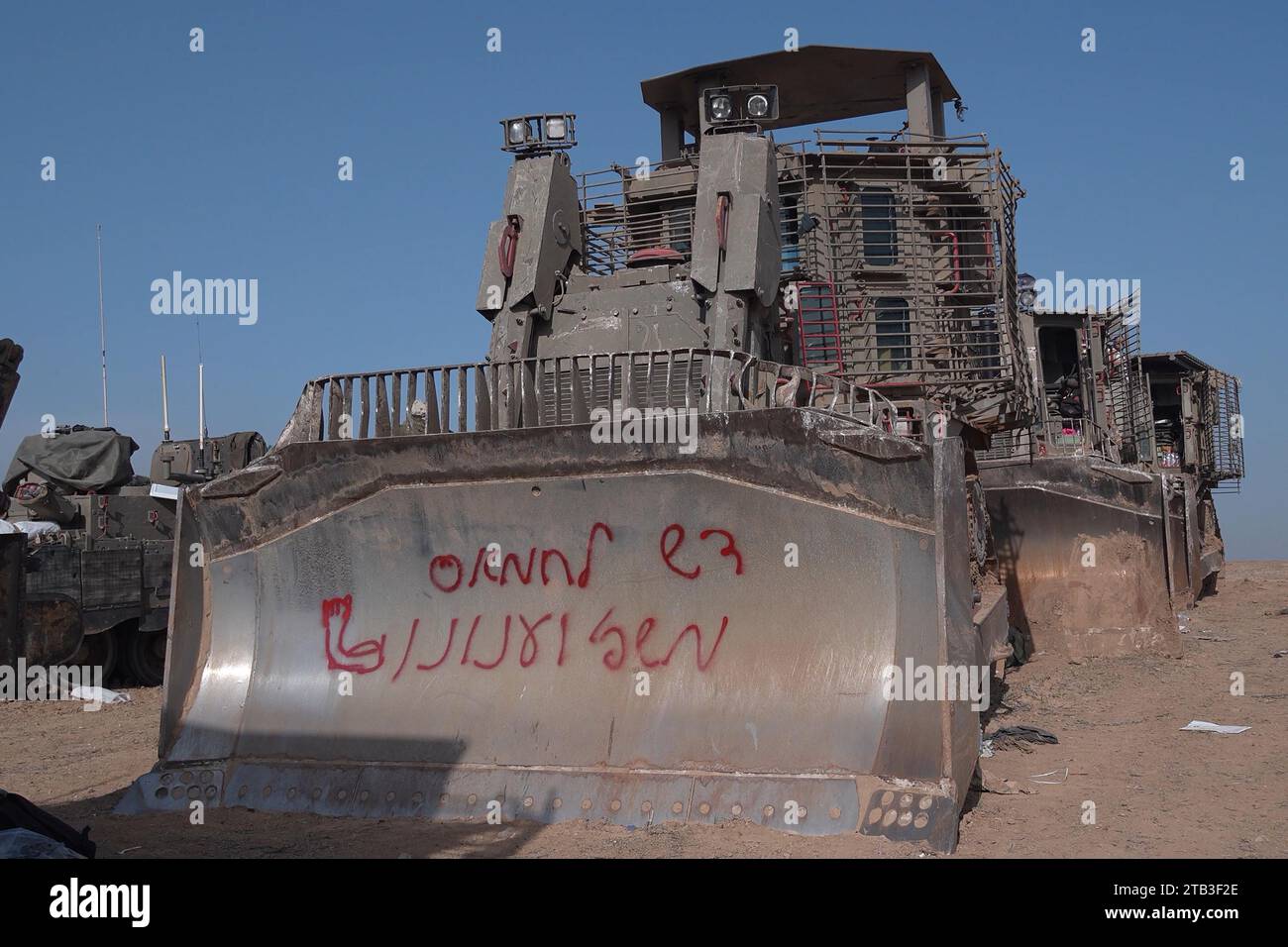 An Israeli D9 armored military bulldozer with a graffiti in red reads ...