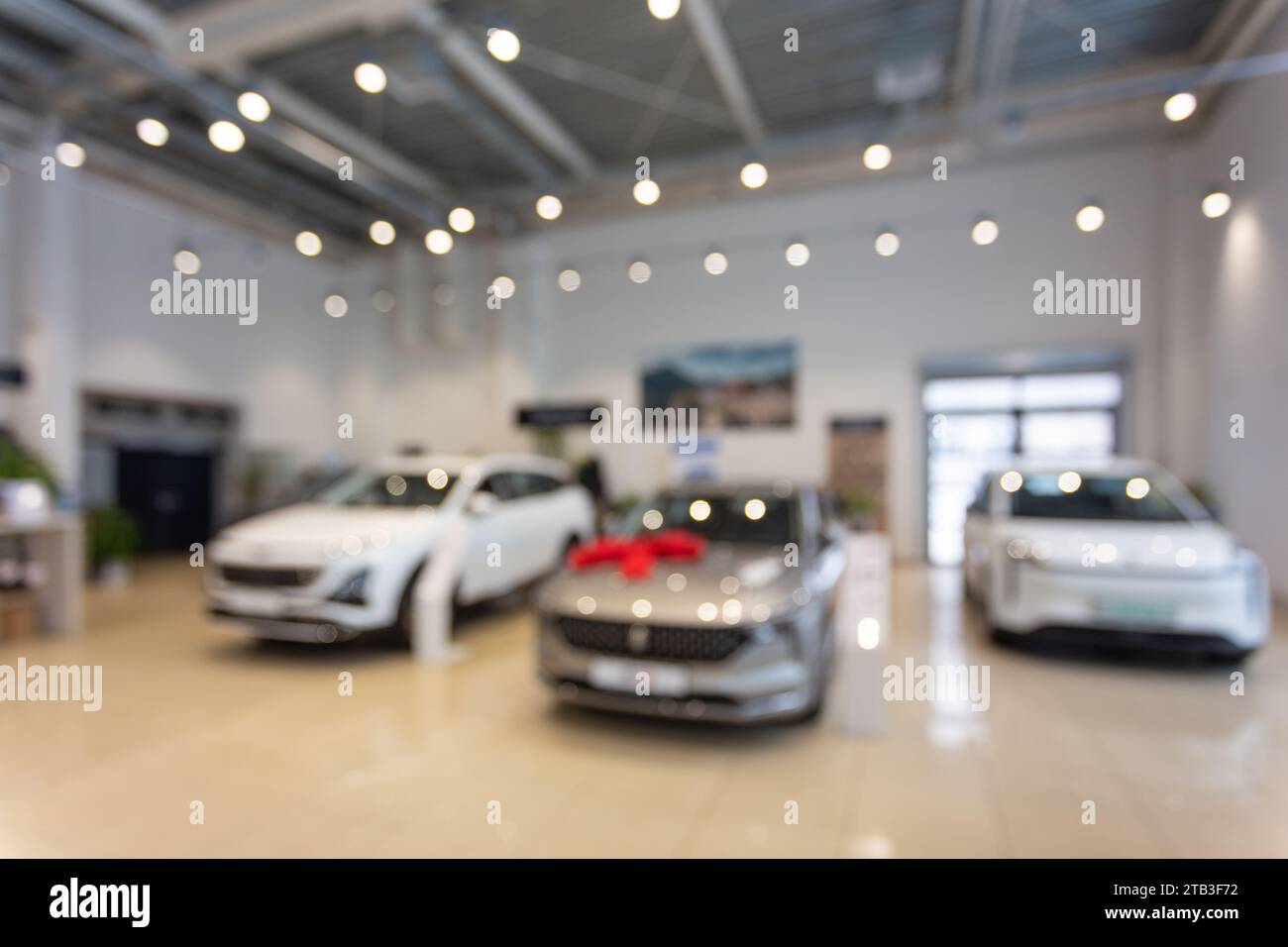 Blurred new car parked in modern showroom waiting for sales. Abstract ...