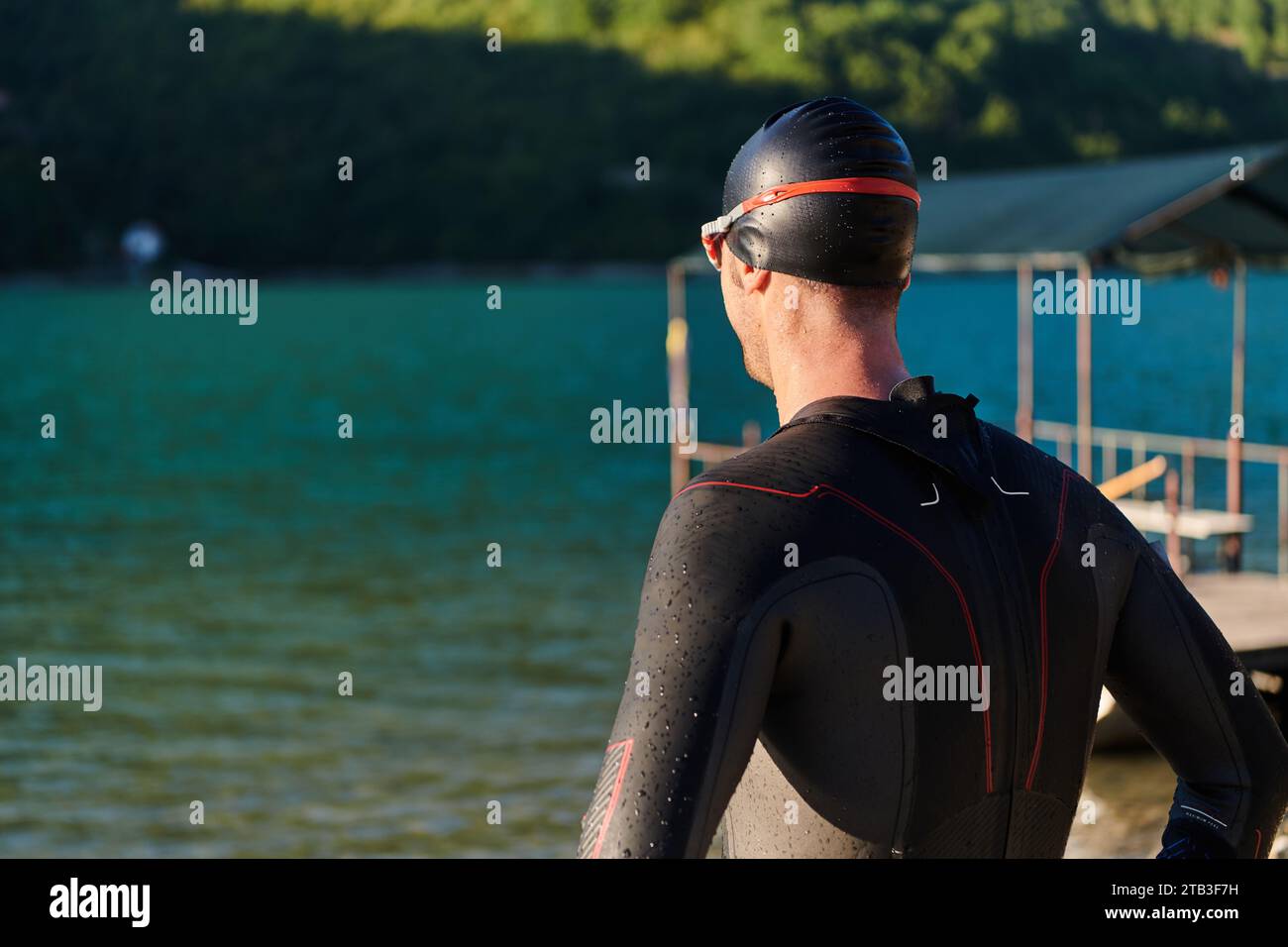 Authentic triathlon athlete getting ready for swimming training on lake ...