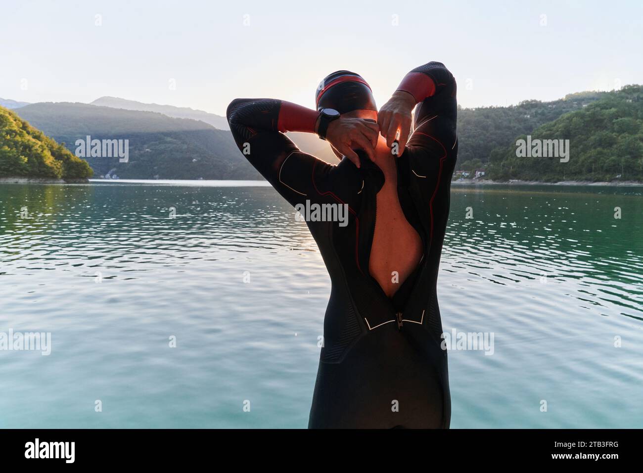 Authentic triathlon athlete getting ready for swimming training on lake ...