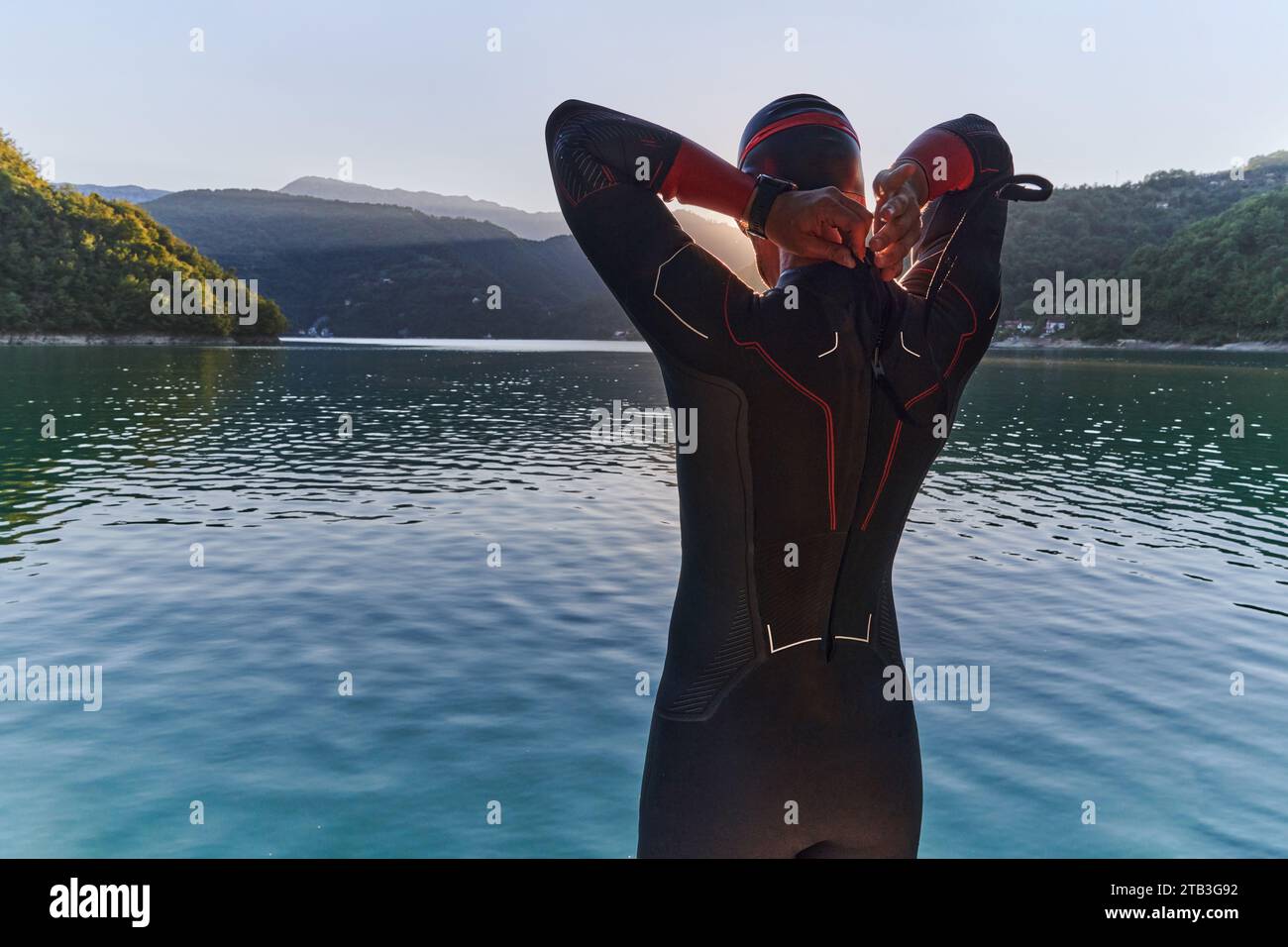 Authentic triathlon athlete getting ready for swimming training on lake ...