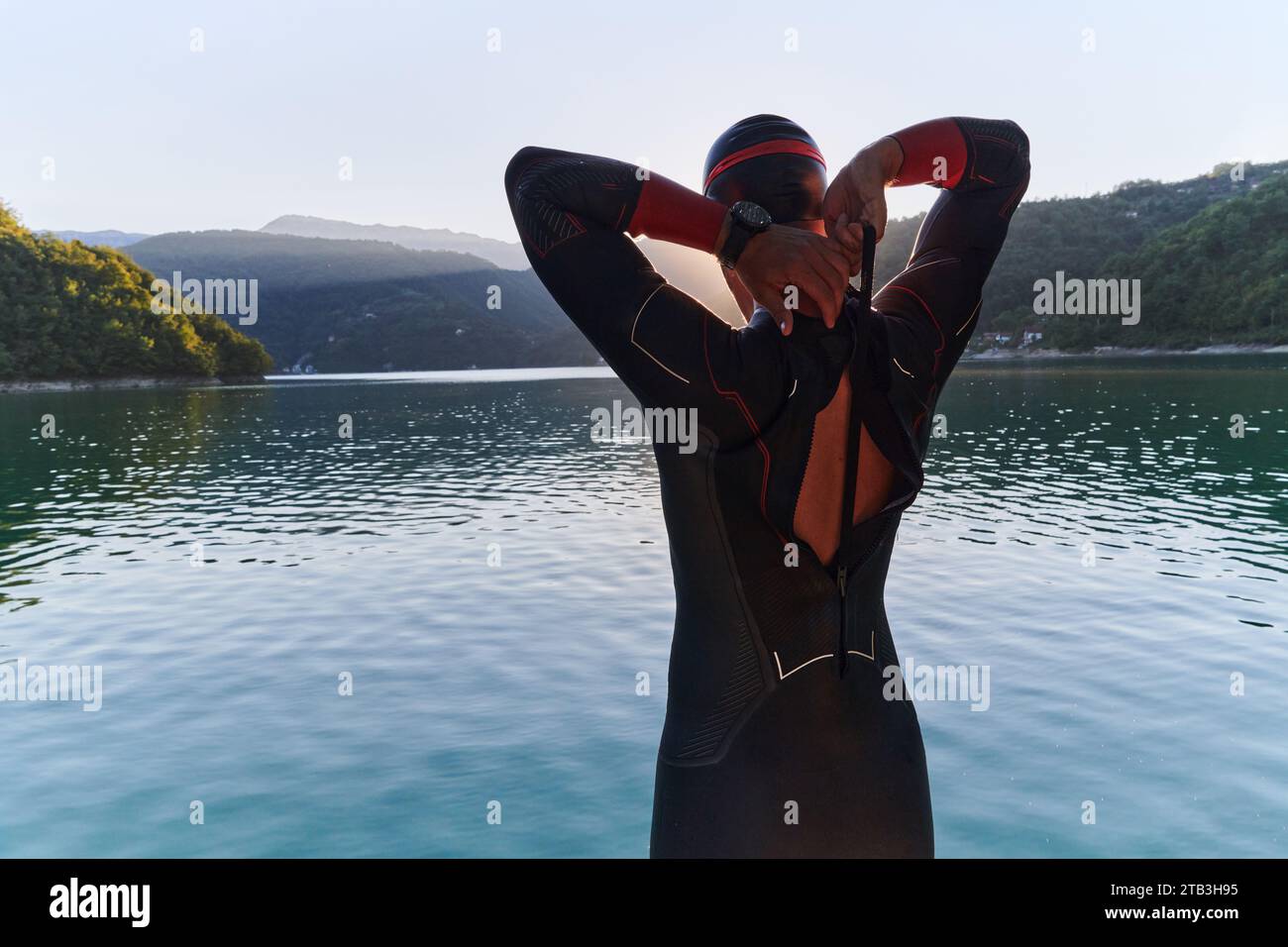Authentic triathlon athlete getting ready for swimming training on lake ...