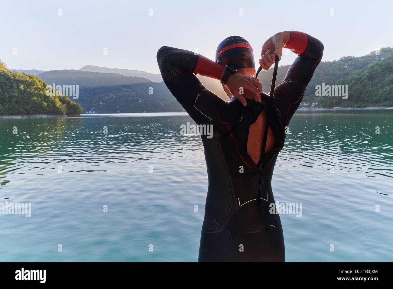 Authentic triathlon athlete getting ready for swimming training on lake ...