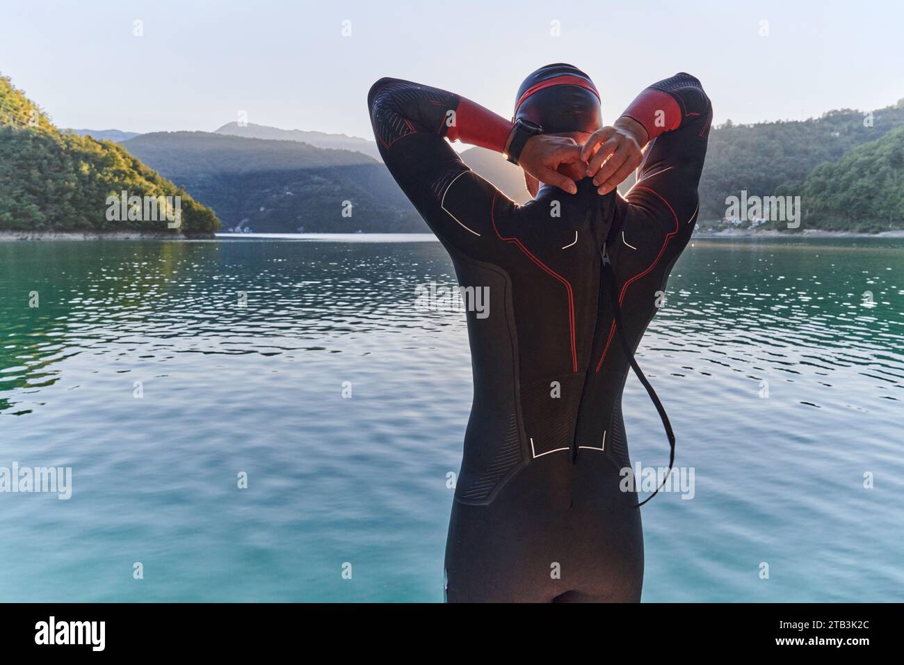 Authentic triathlon athlete getting ready for swimming training on lake ...