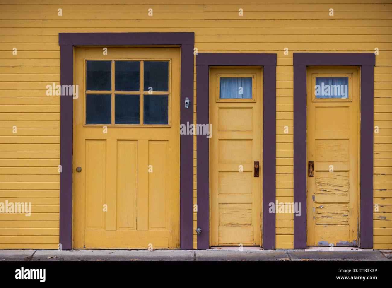 Close up of three doors on the side of a building where two are thinner ...