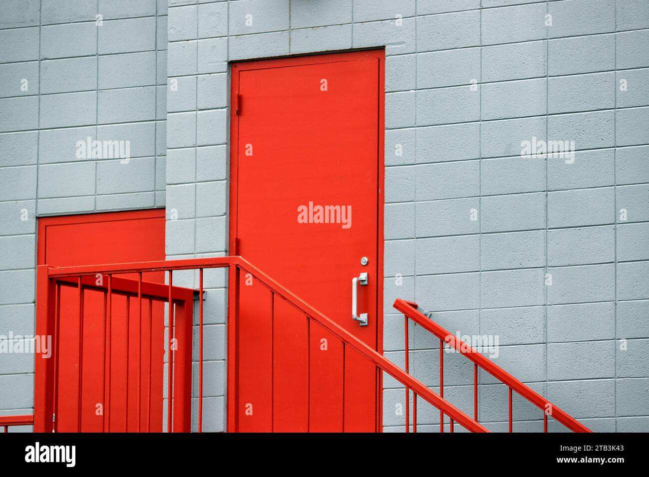 White brick building with two orange red doors and railing Stock Photo ...
