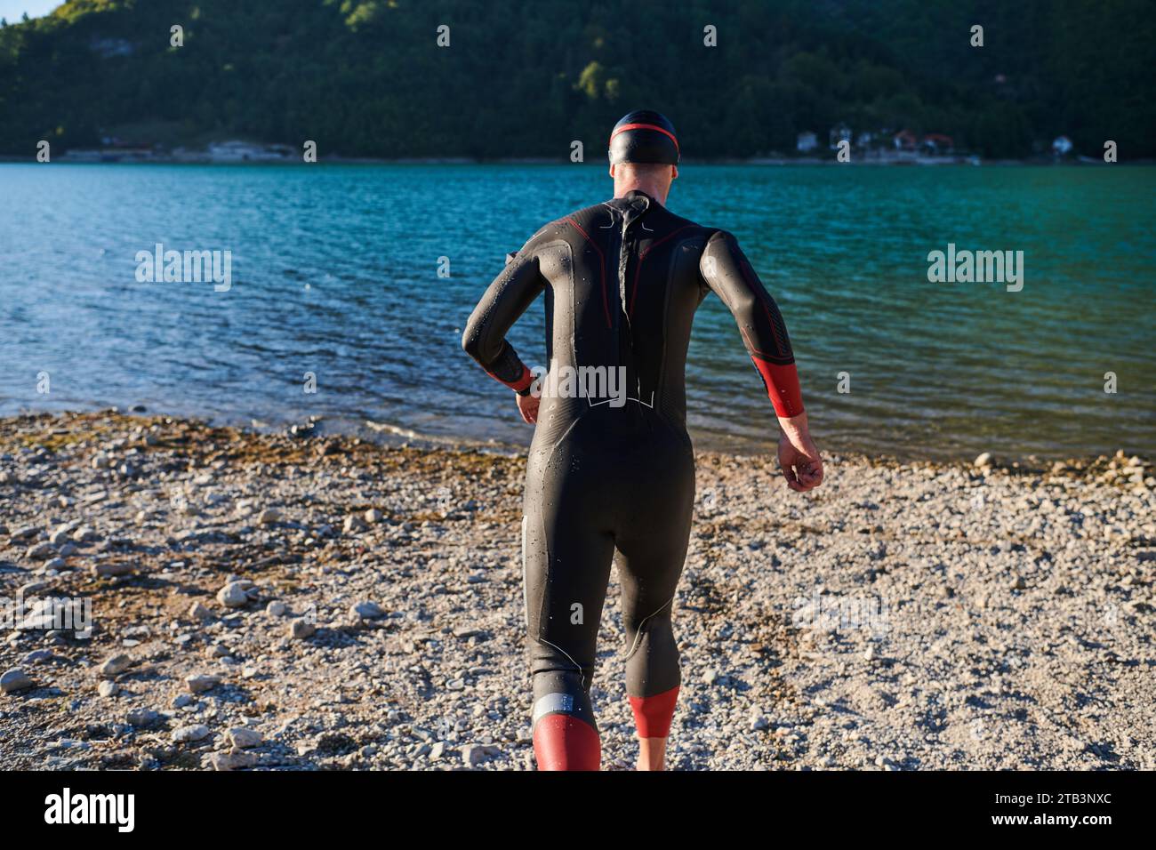 Authentic triathlon athlete getting ready for swimming training on lake ...