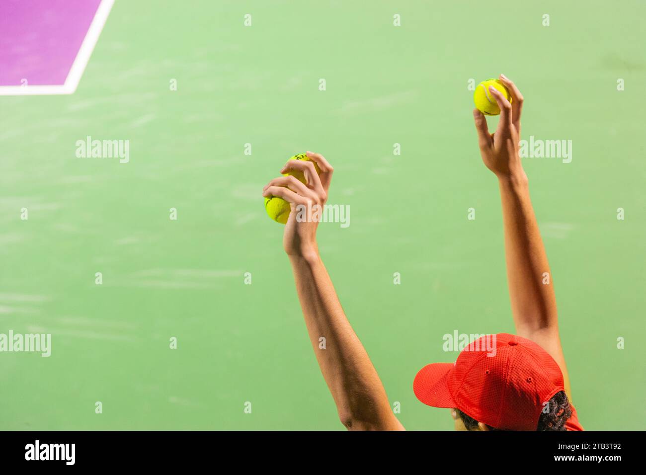 Ball boy holding tennis balls with arms raised in a professional tennis ...