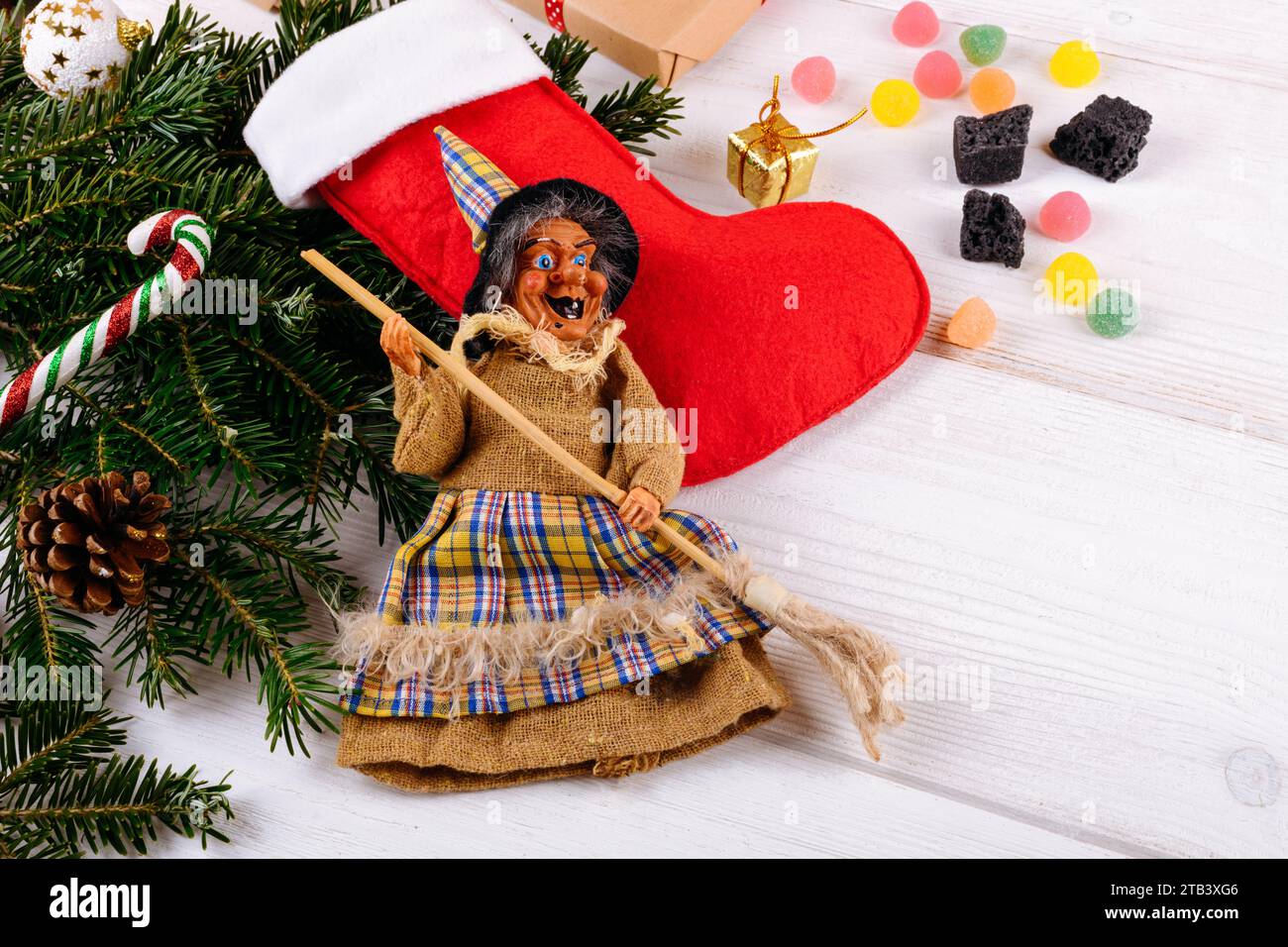 The witch Befana and red stocking with sweet coal and candy on white ...