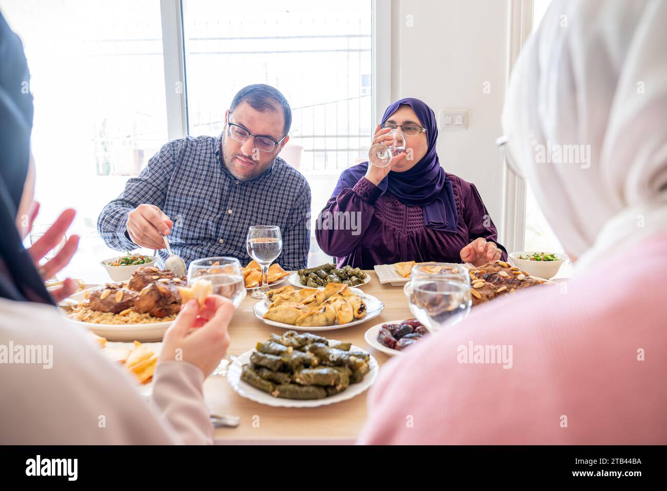 Arabian family having dinner together on wooden table with father ...