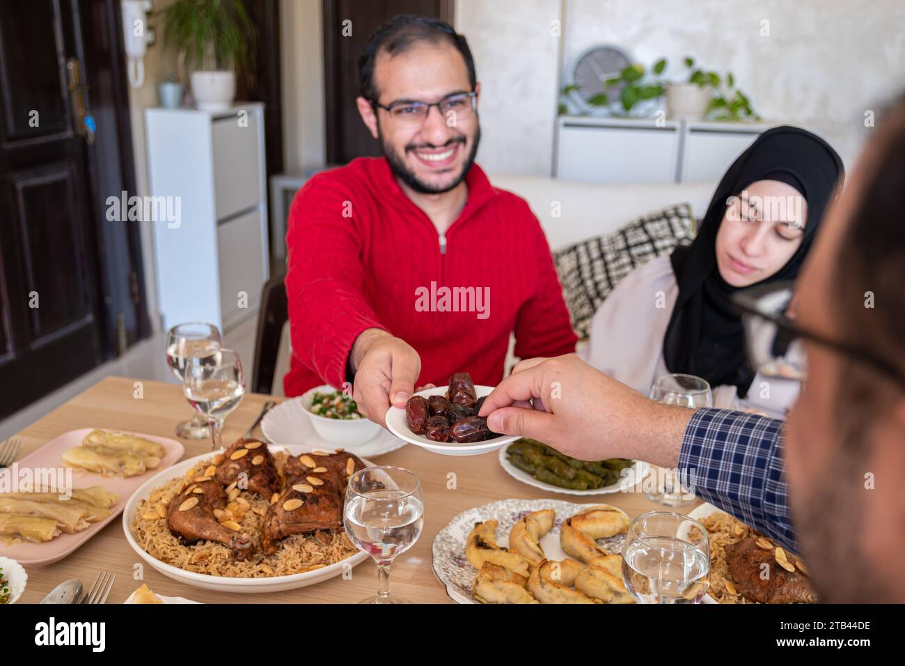 Young male eating dates on dining table with his family during iftar ...