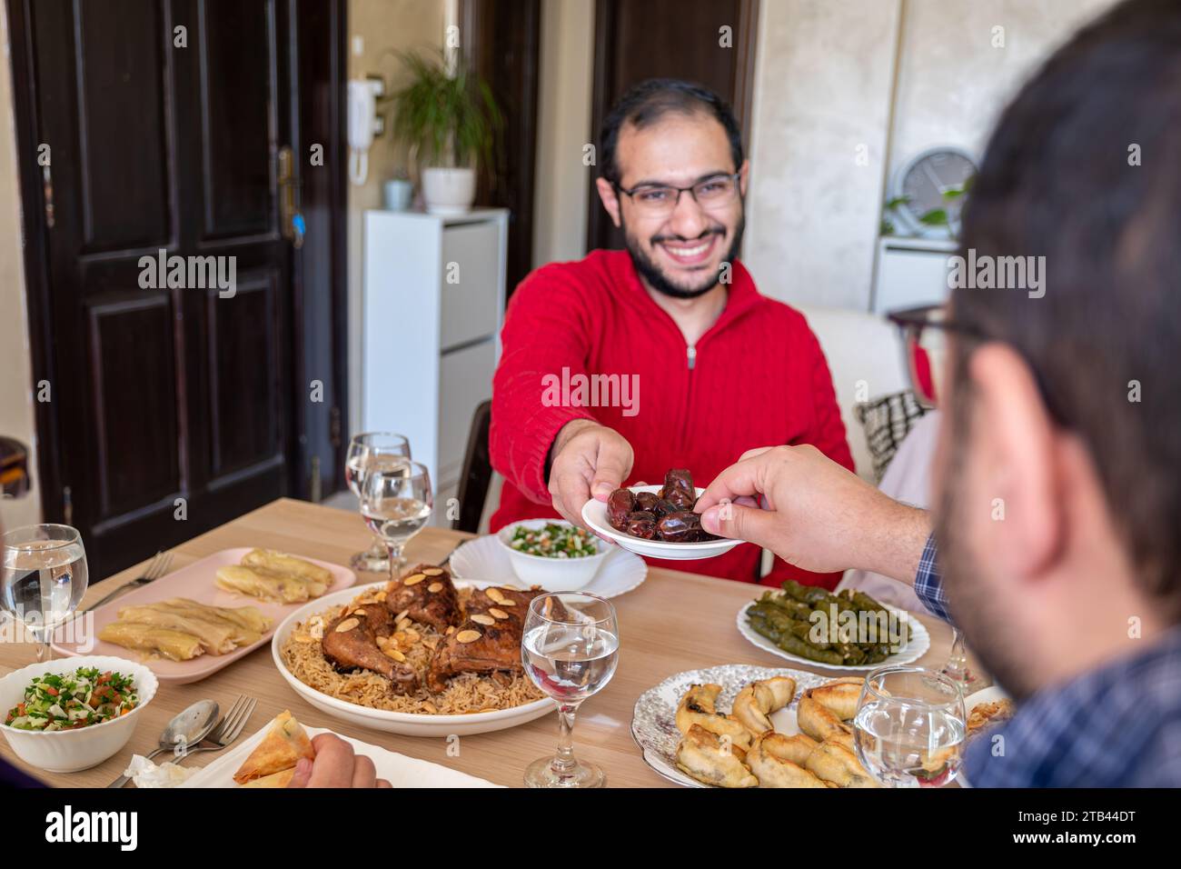 Young male eating dates on dining table with his family during iftar ...