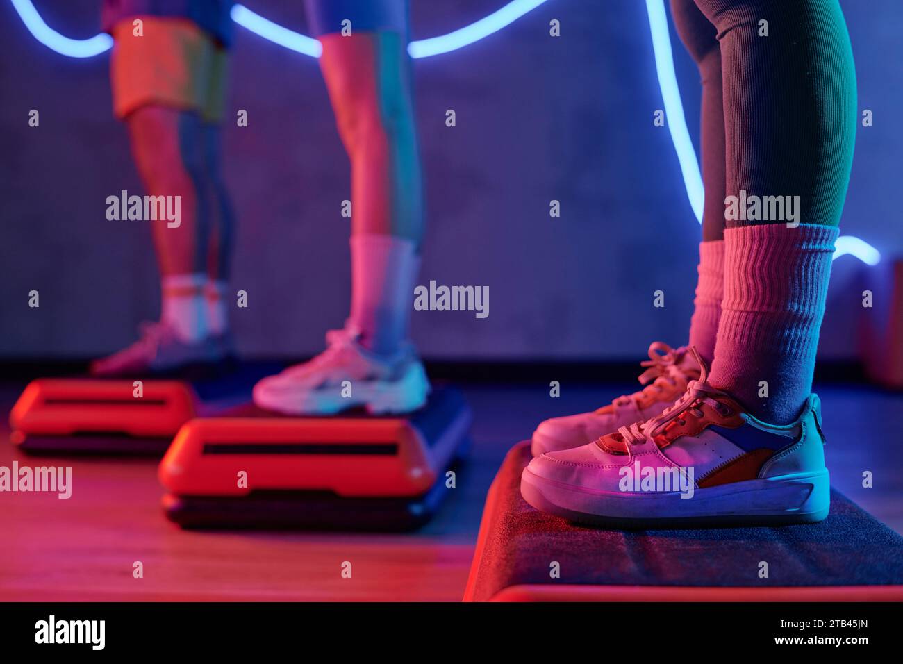 Legs of unrecognizable gym goers calmly standing on step platforms at ...
