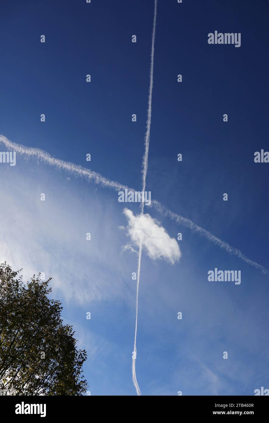 long white trails high in the blue sky crossing a cloud without ...