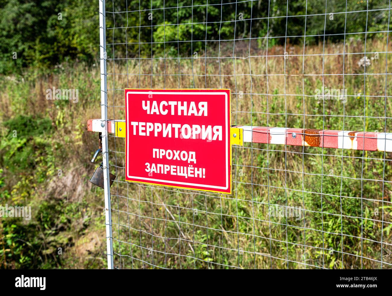 Warning sign on the fence. Text in russian: Private Territory. No ...