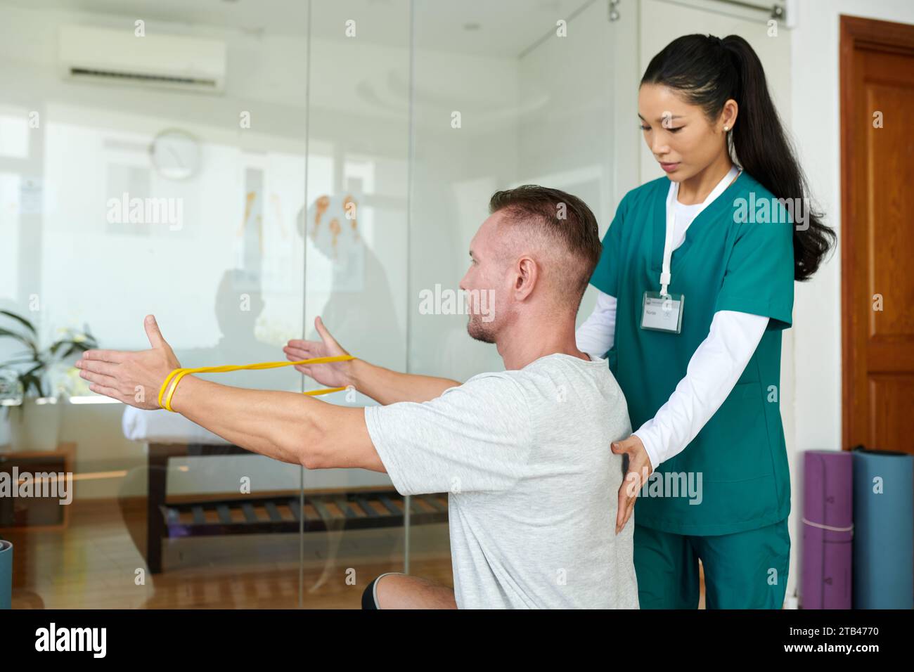 Rehab nurse telling patient to keep back straight when exercising with ...