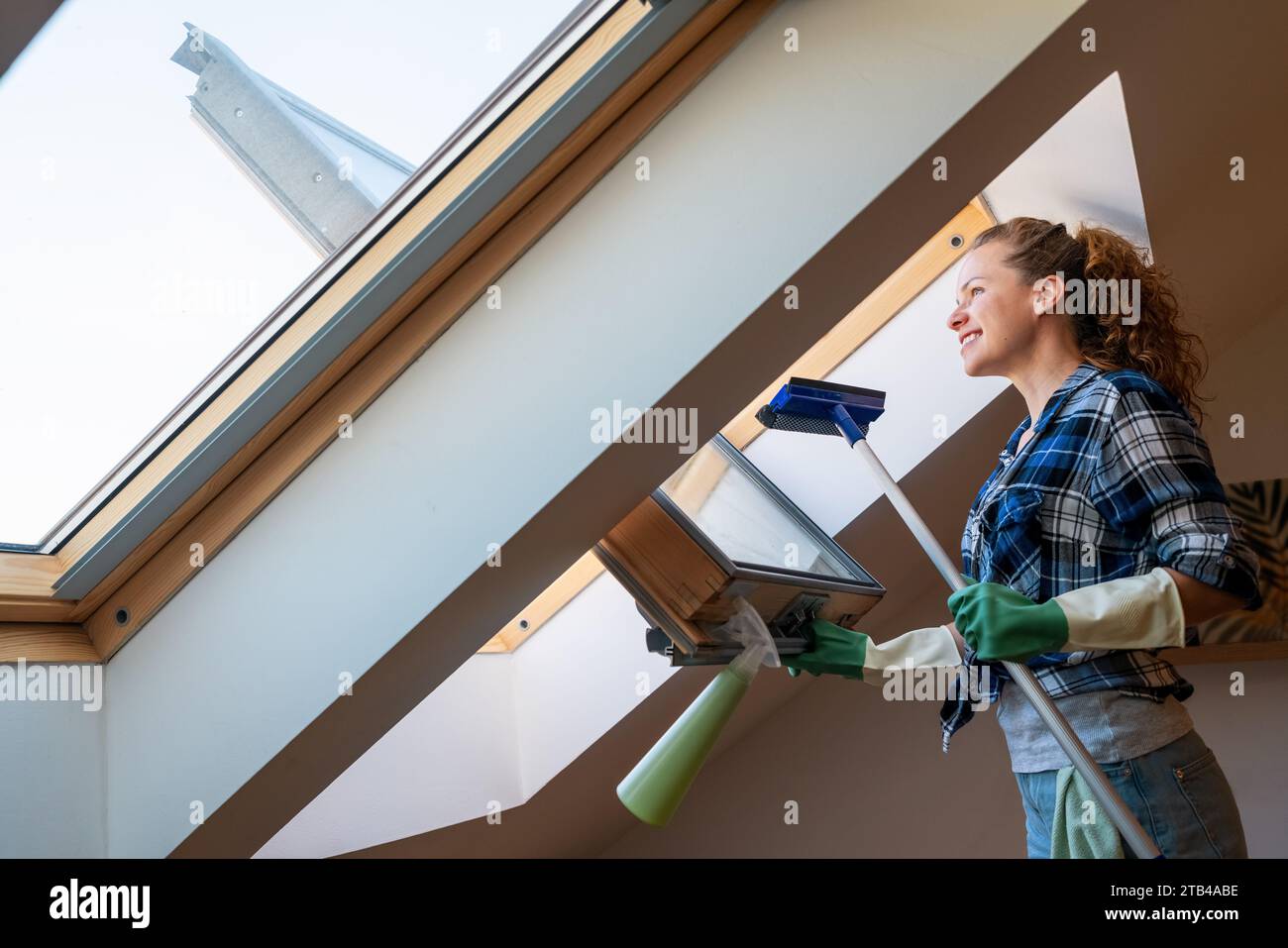 Woman cleans skylight window in her apartment. Housework, cleaning ...