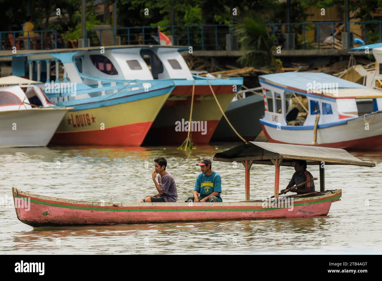 Men on wooden canoe with awning in the port of this provincial capital ...