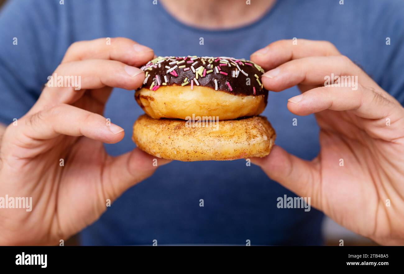 Man holding two donuts in his hands. Sandwich of chocolate doughnuts ...