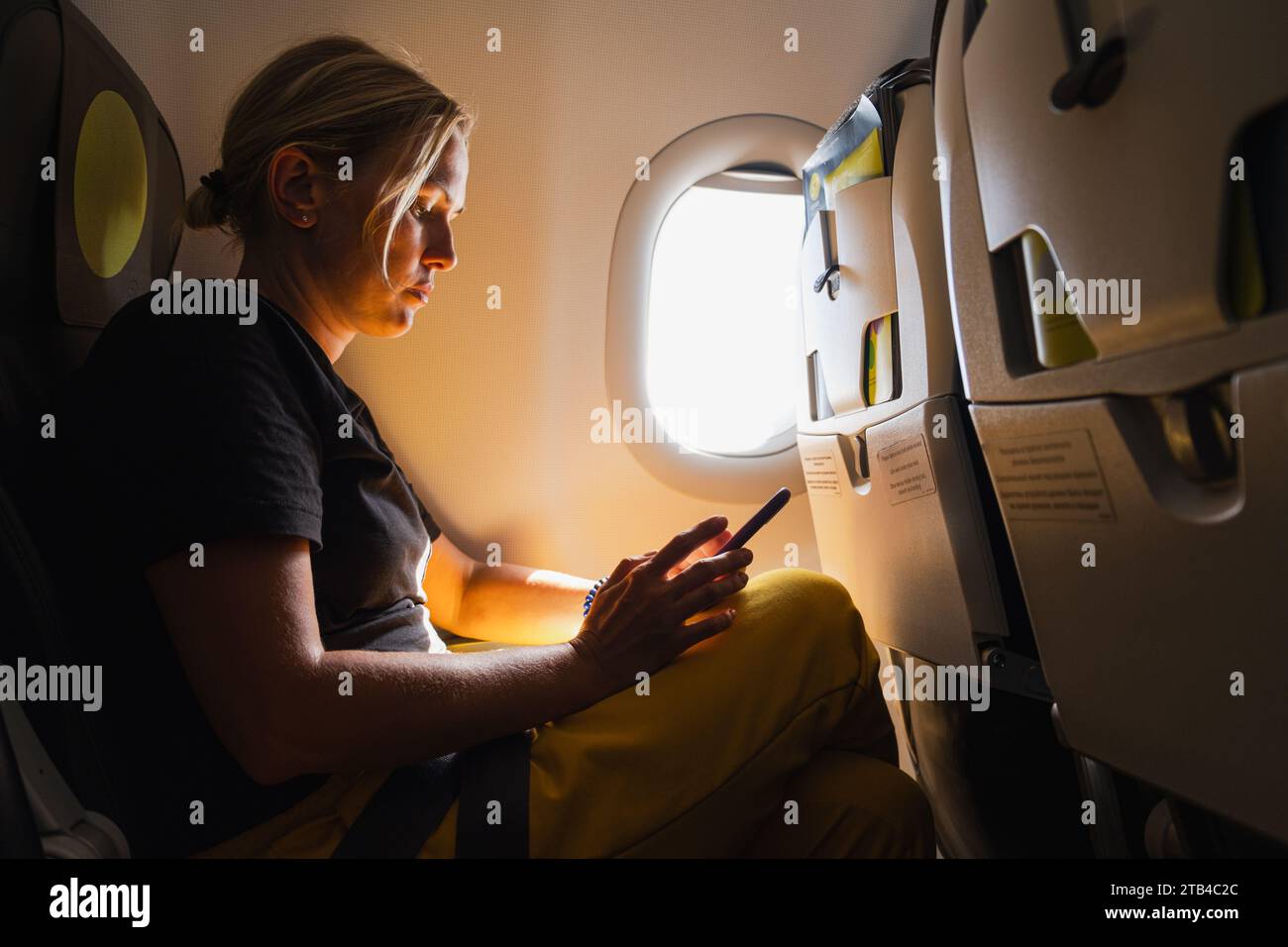 Passenger woman is flying in plane. Girl using phone sitting by ...