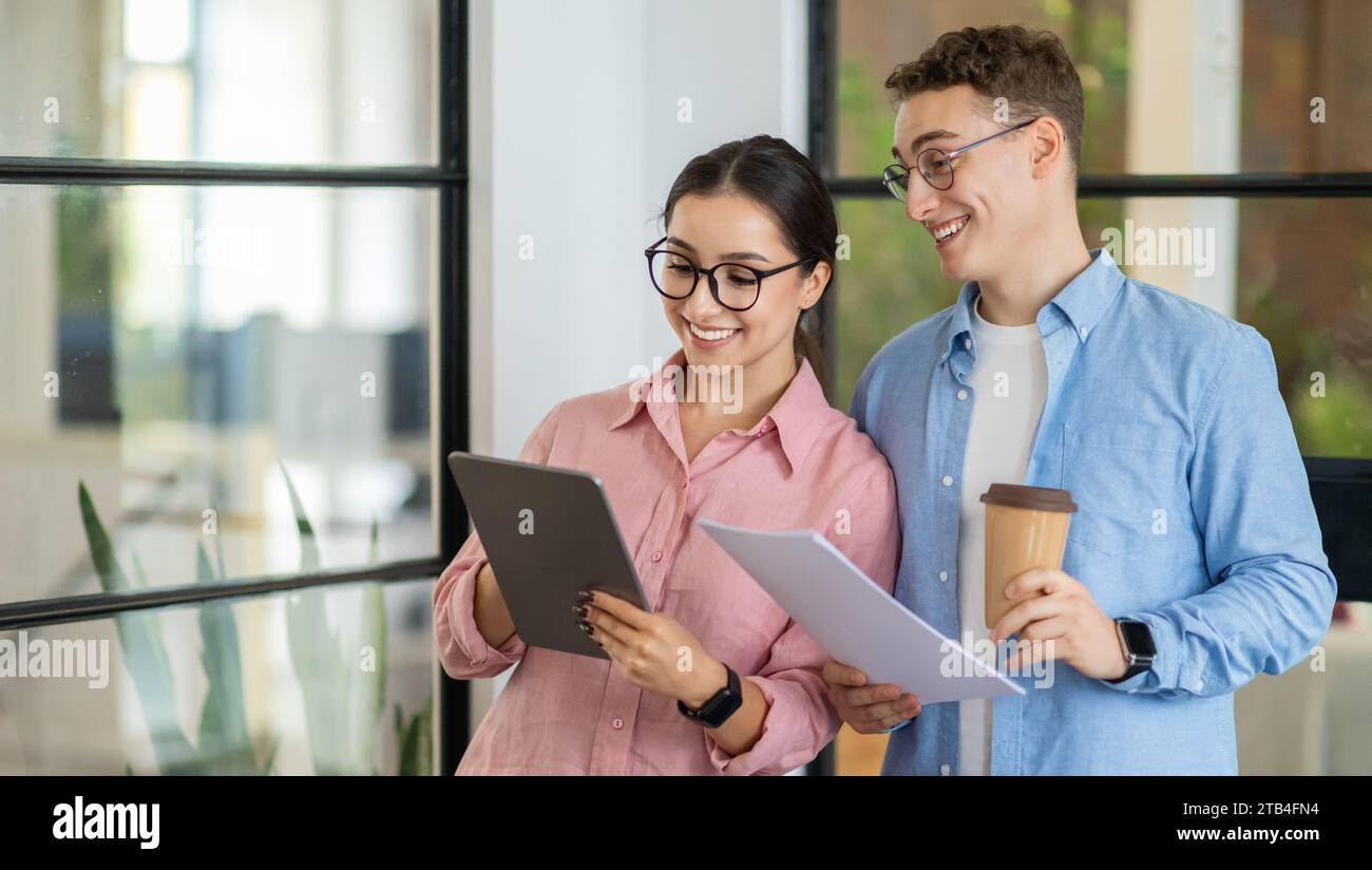 Smiling young diverse people managers look at tablet, planning startup ...