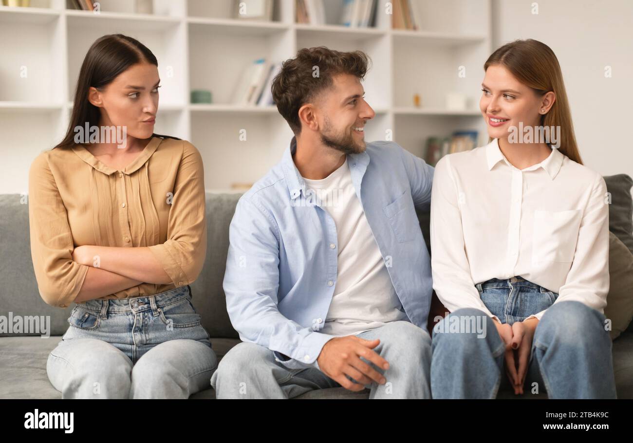 Jealous Lady Looking At Flirting Couple Sitting Together At Home Stock ...