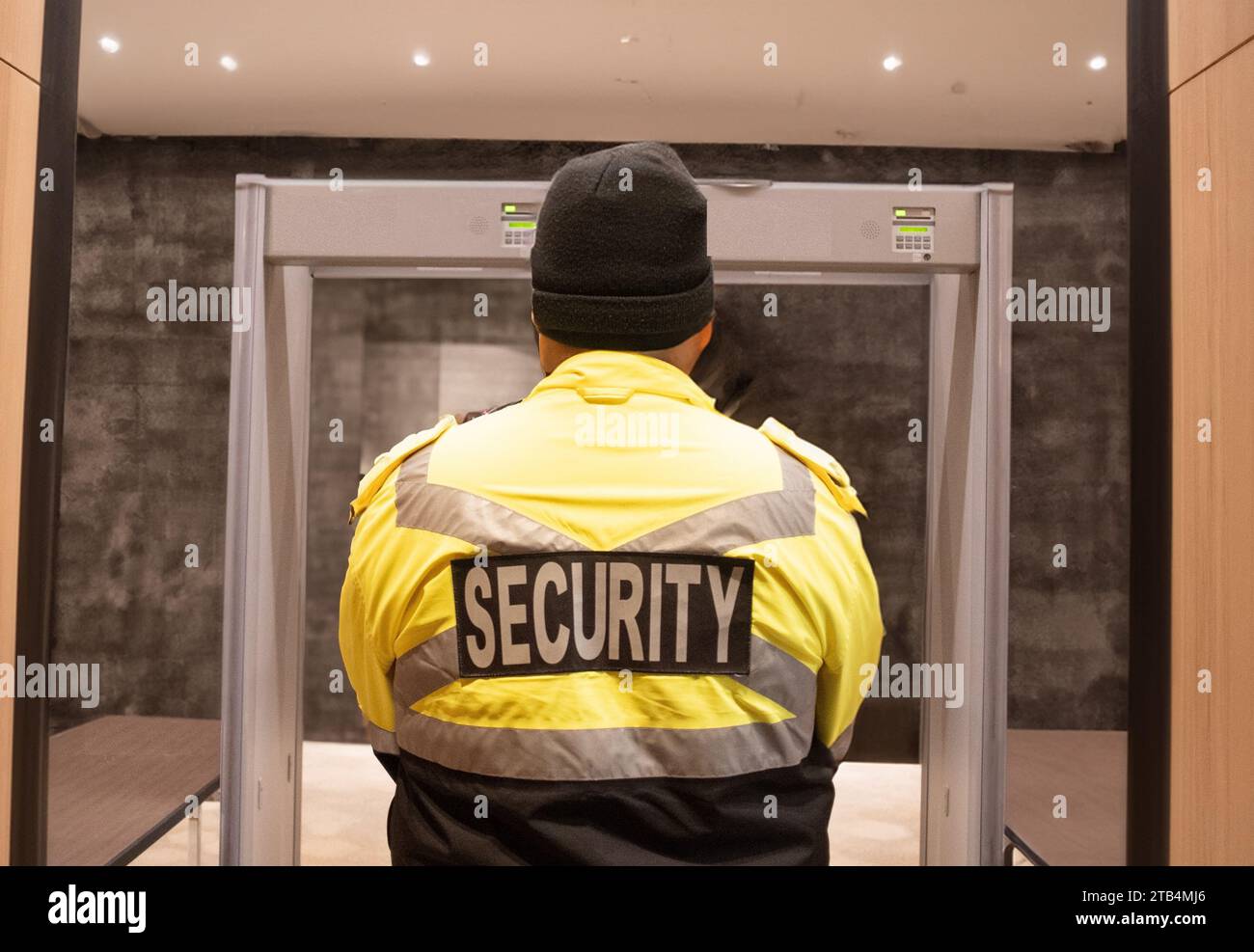 A security guard stationed with metal detectors at an office entrance ...