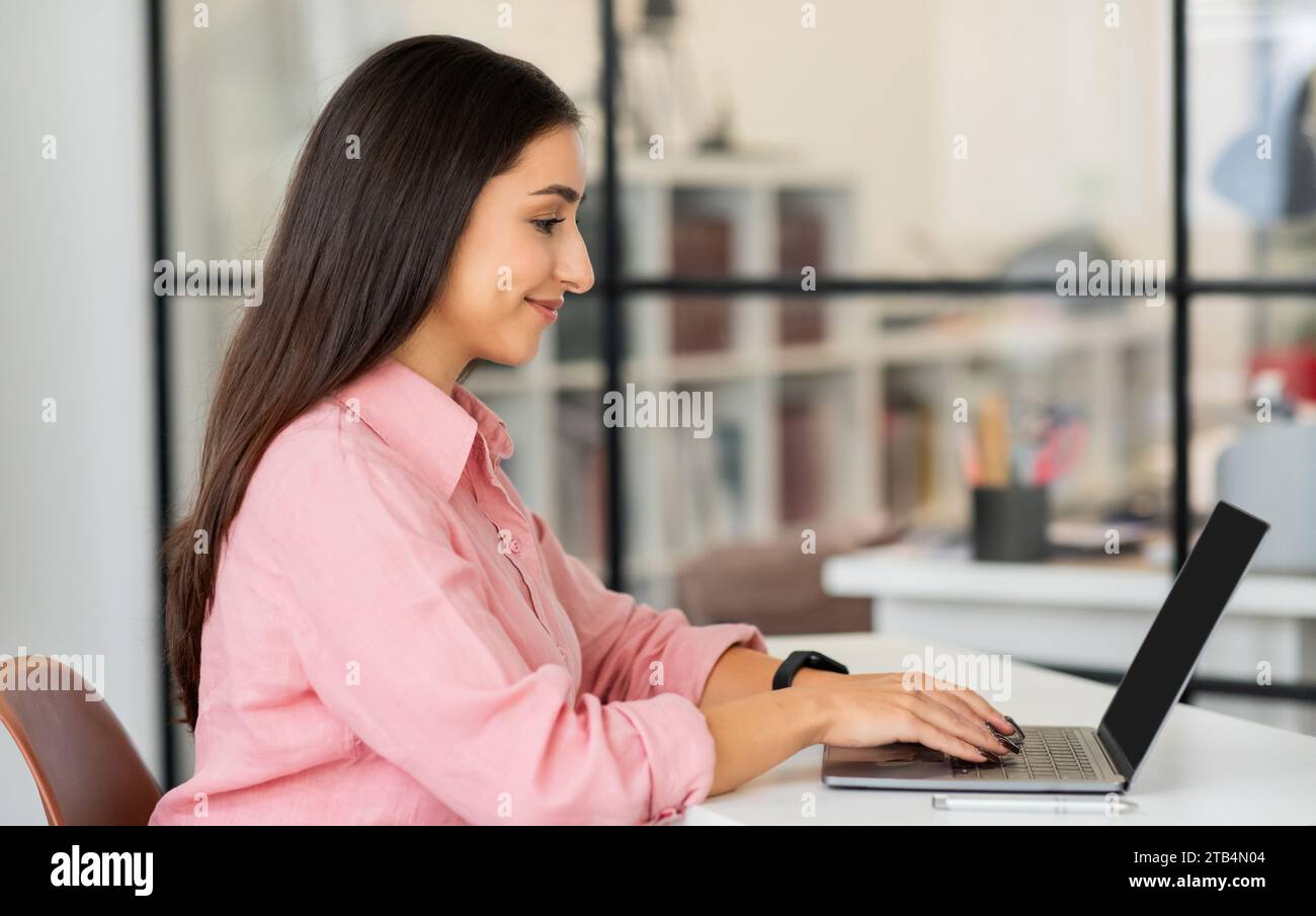 Smiling pretty millennial middle eastern woman manager typing on ...