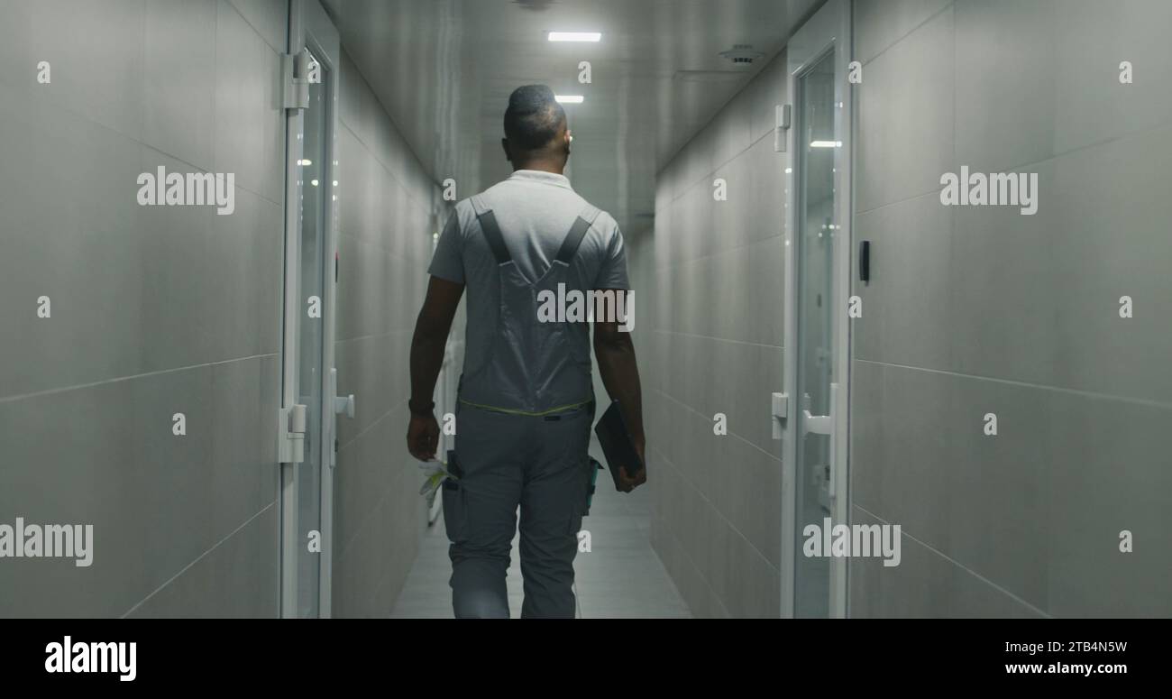 African American engineer in uniform holds tablet computer, walks in ...