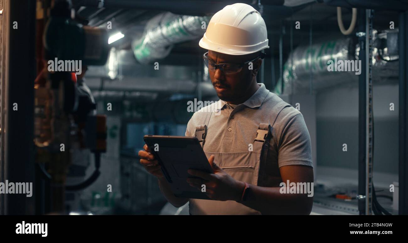 Male technician worker wearing safety uniform and hard hat works using ...