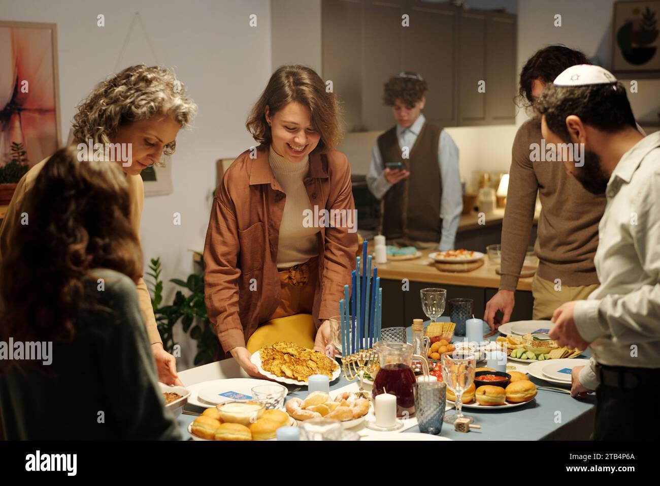 Happy Jewish family putting plates with homemade food on table while ...