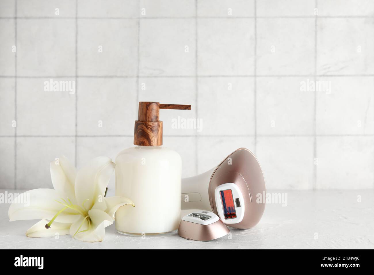 Modern photoepilator with attachment, soap in bottle and lily flower on ...