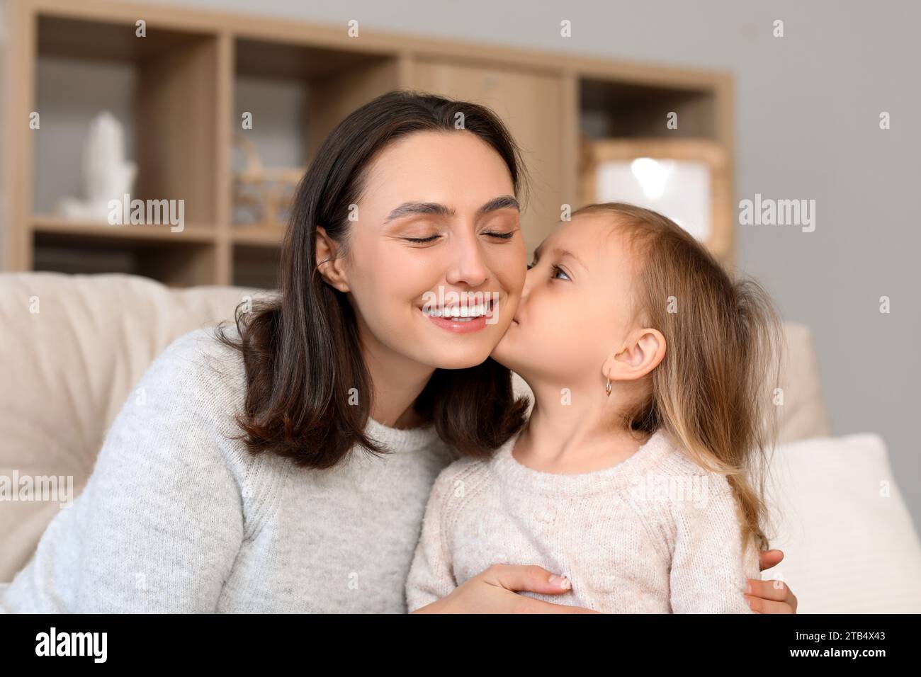 Cute little daughter kissing her beautiful mother at home Stock Photo ...