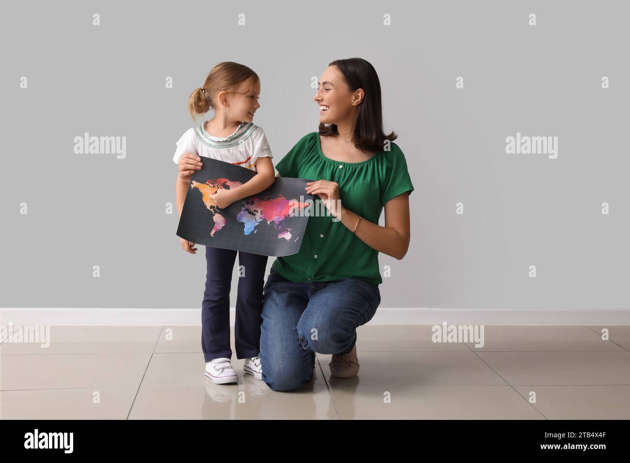Beautiful mother and her cute little daughter pointing at world map ...