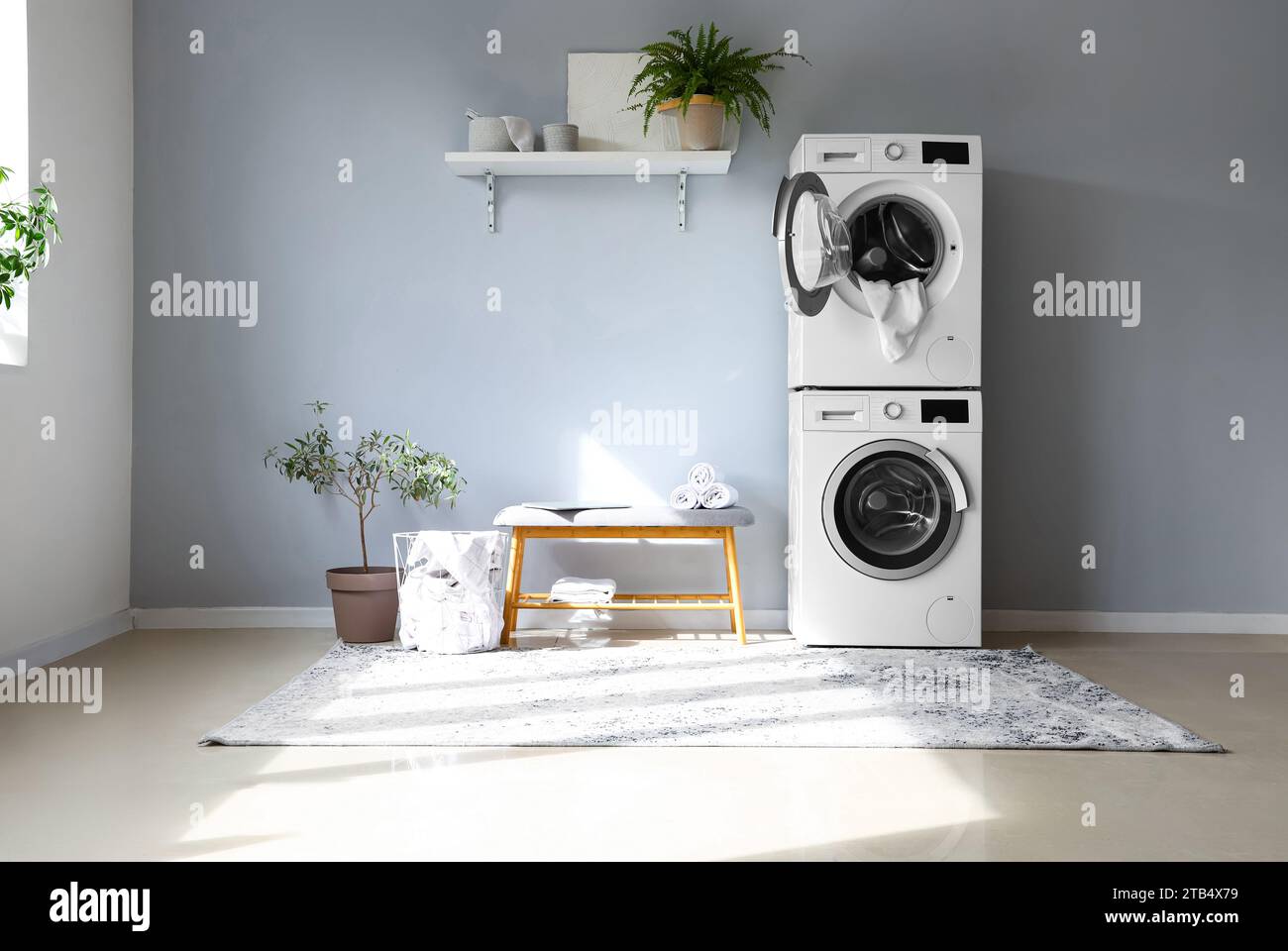 Interior of modern laundry room with washing machines and grey bench ...