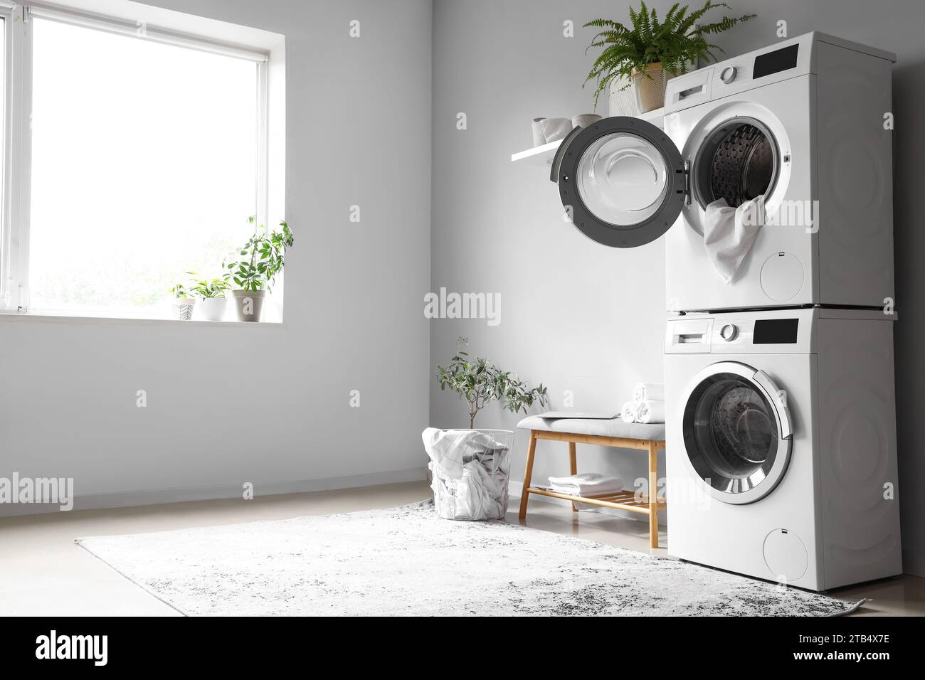 Interior of modern laundry room with washing machines and grey bench ...