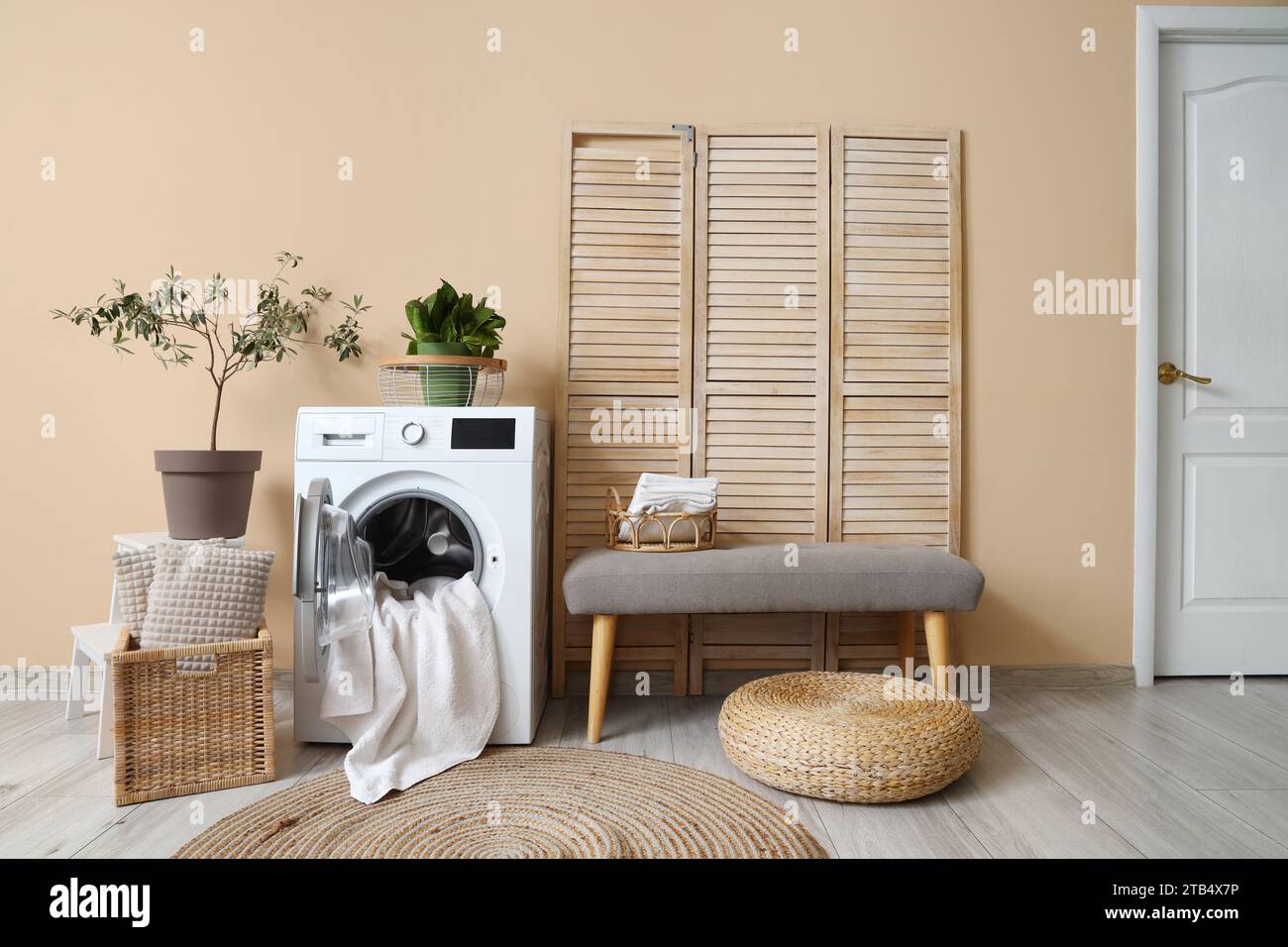 Laundry room interior with washing machine, grey bench and houseplants ...