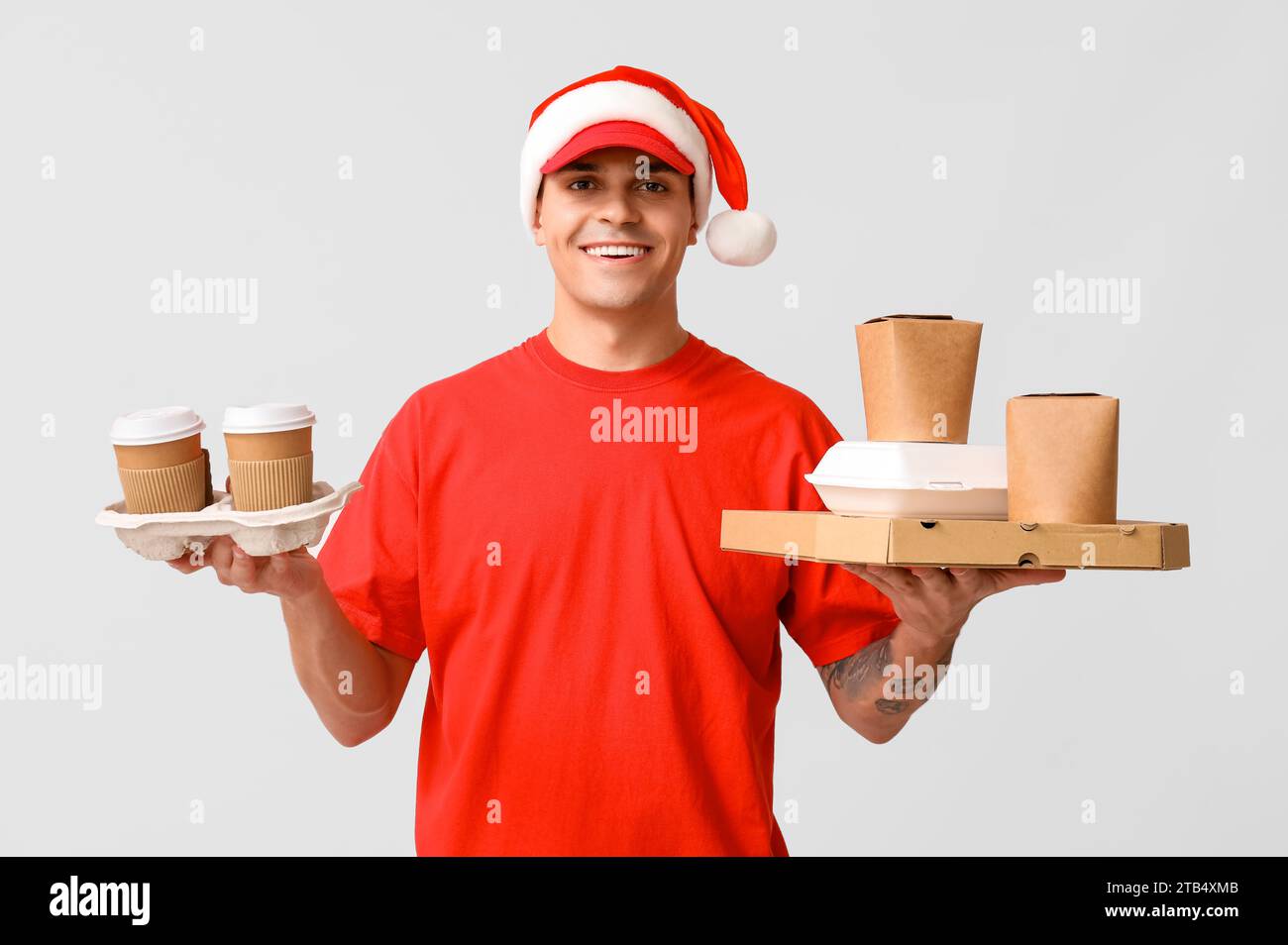 Delivery man in Santa hat with food order and cups of coffee on white background Stock Photo - Alamy