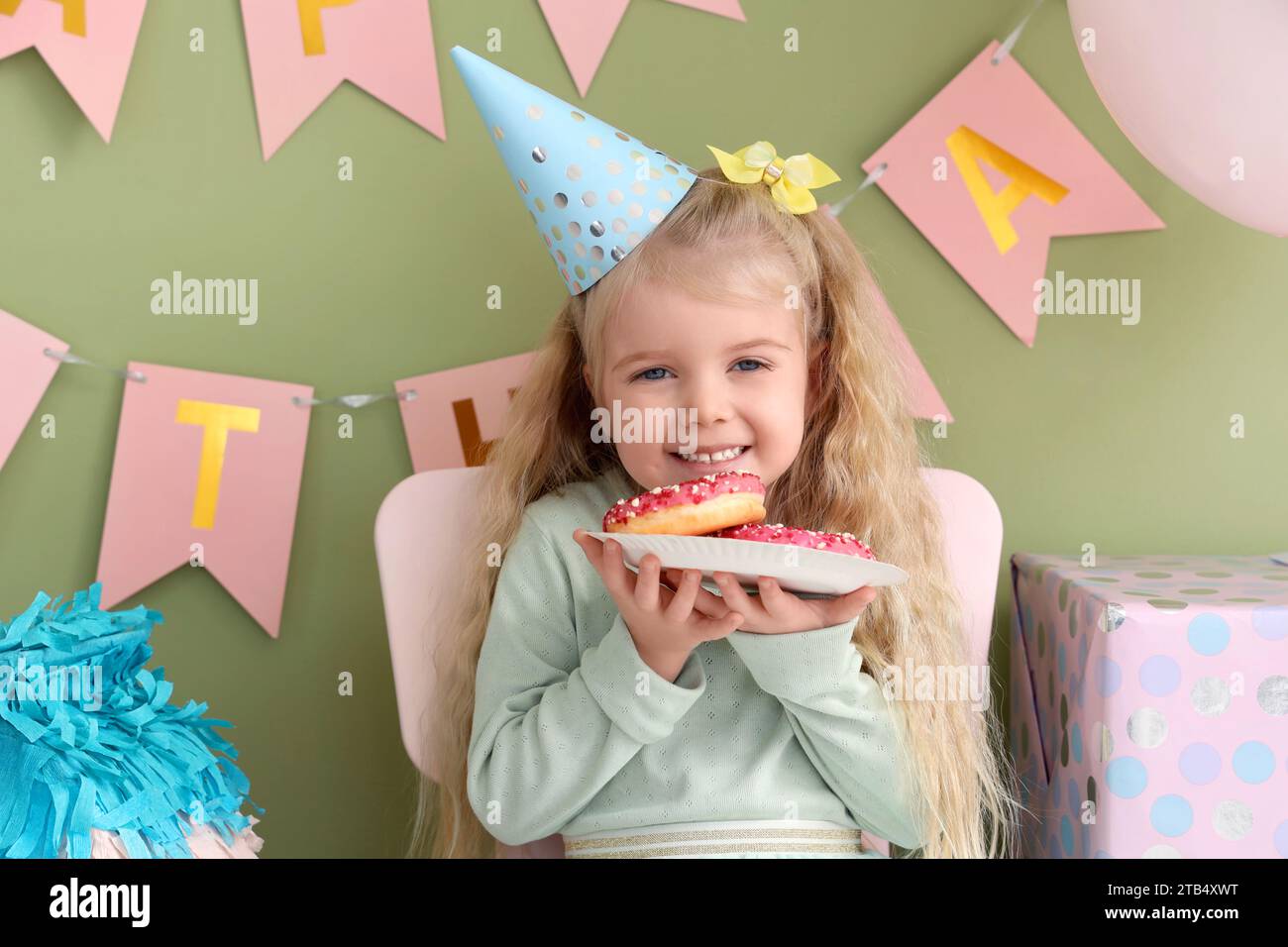 Cute little girl in party hat with donuts celebrating Birthday at home ...
