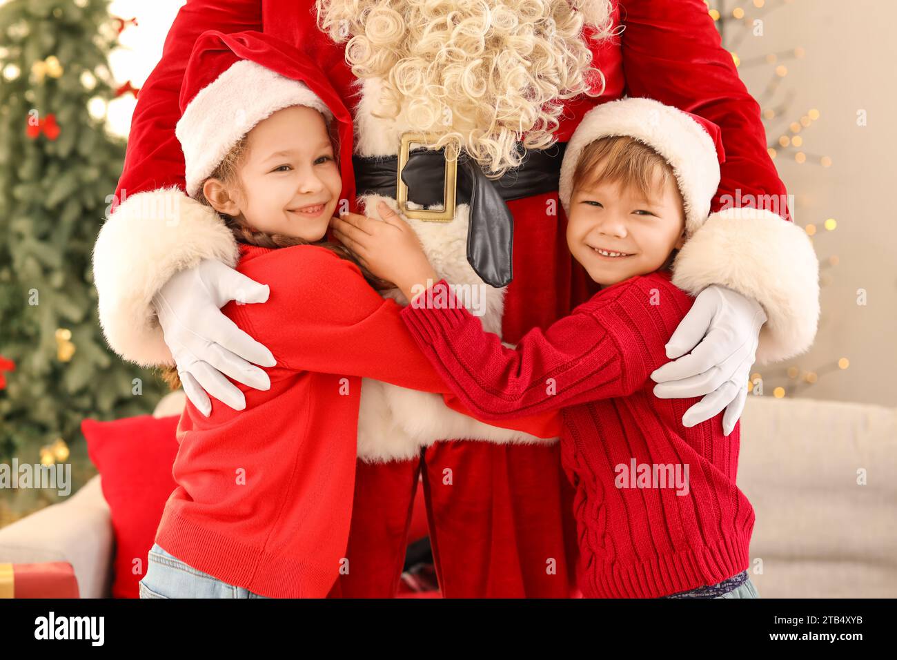 Cute little children hugging Santa Claus at home on Christmas eve Stock ...
